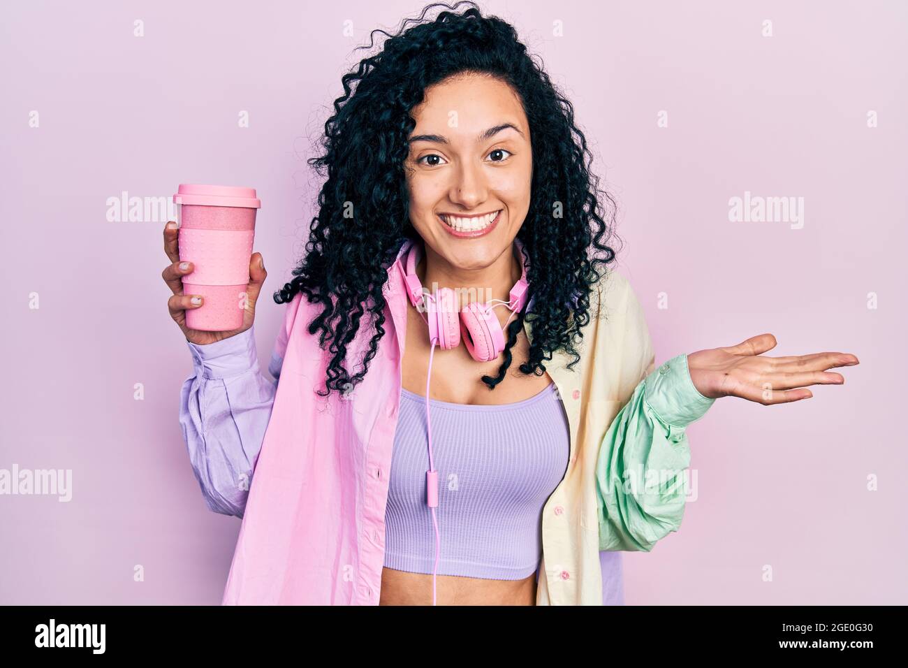 Young hispanic woman with curly hair wearing sportswear and headphones ...