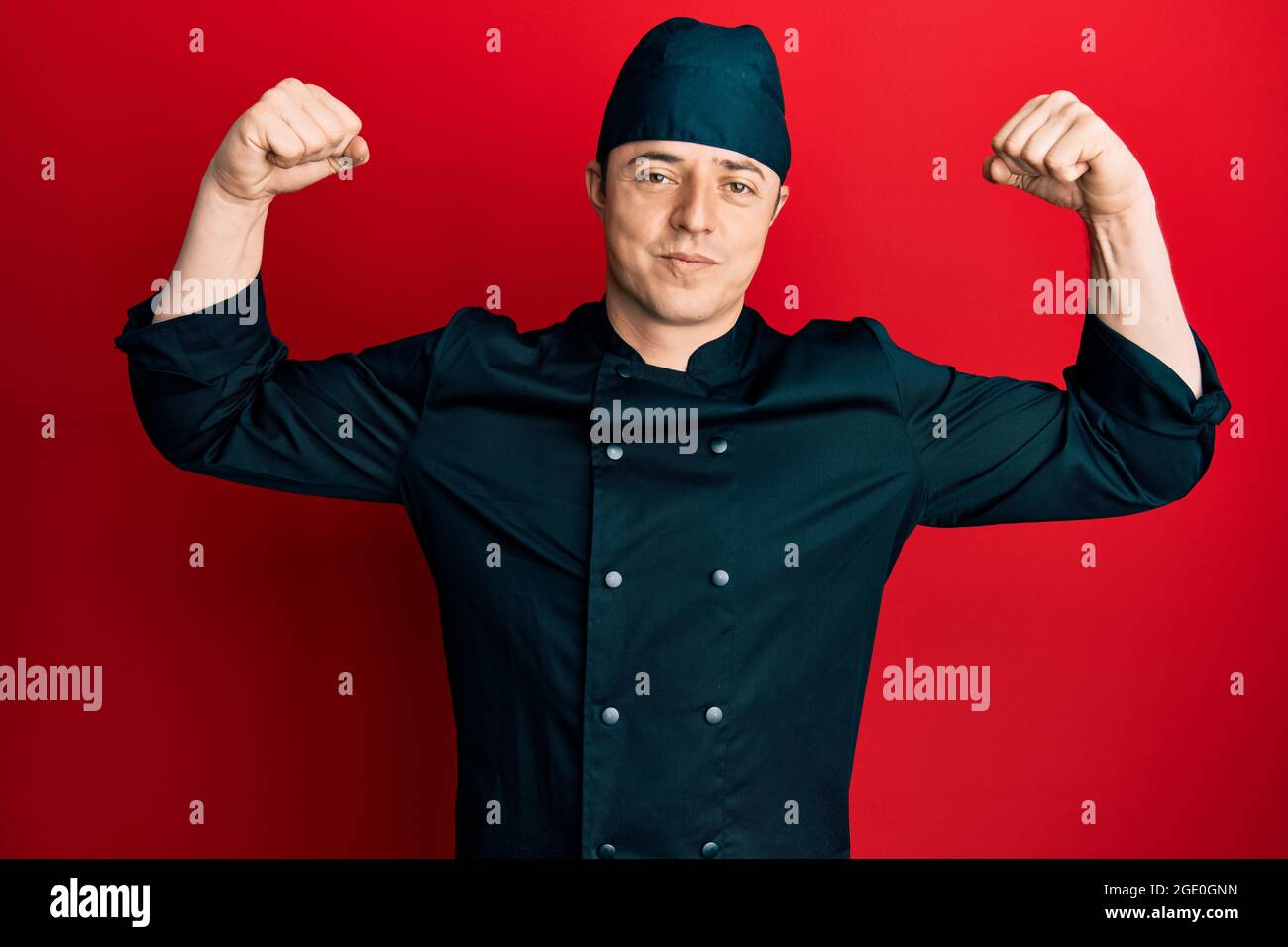 Handsome young man wearing professional cook uniform and hat showing ...