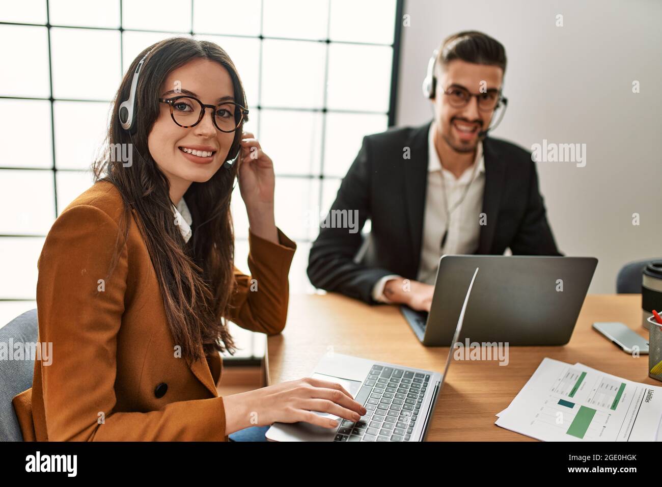 Two hispanic call center agents working at the office Stock Photo - Alamy