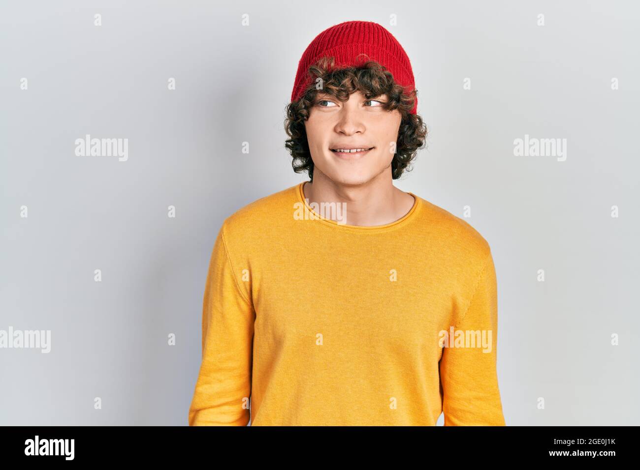 Handsome young man wearing wool hat looking away to side with smile on ...
