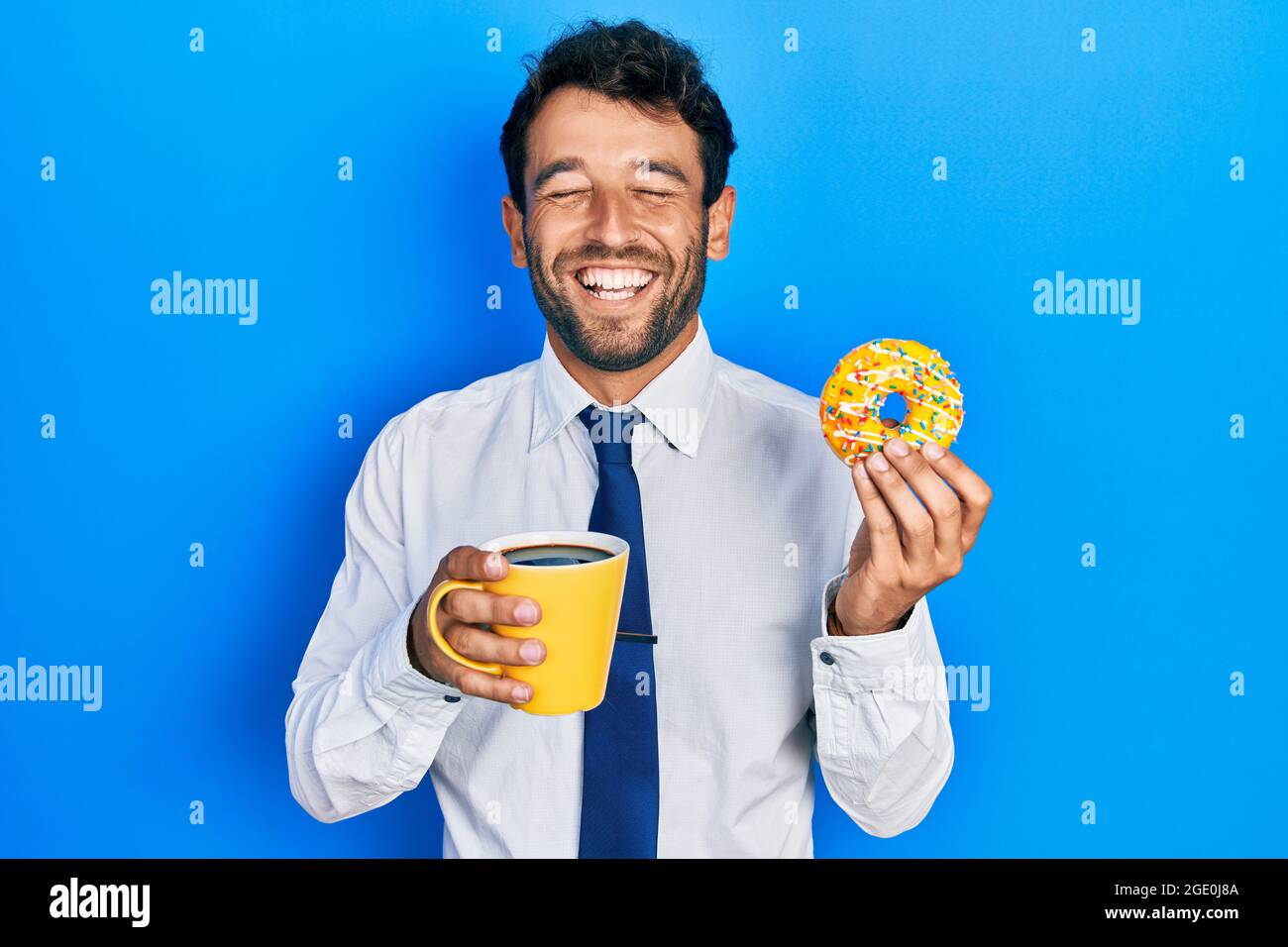 Handsome business man with beard eating doughnut and drinking coffee ...