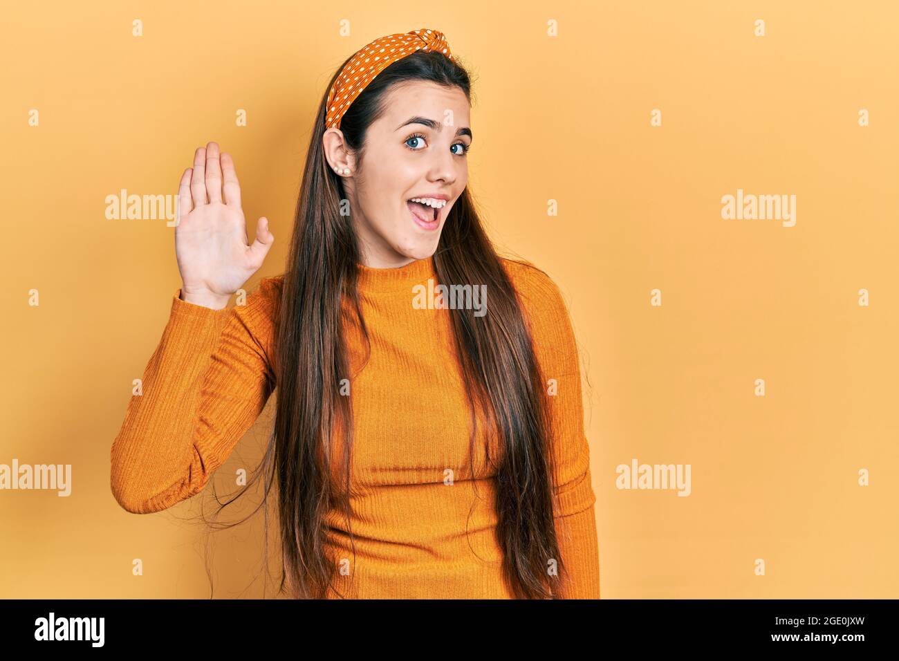Young brunette teenager wearing casual yellow sweater waiving saying ...