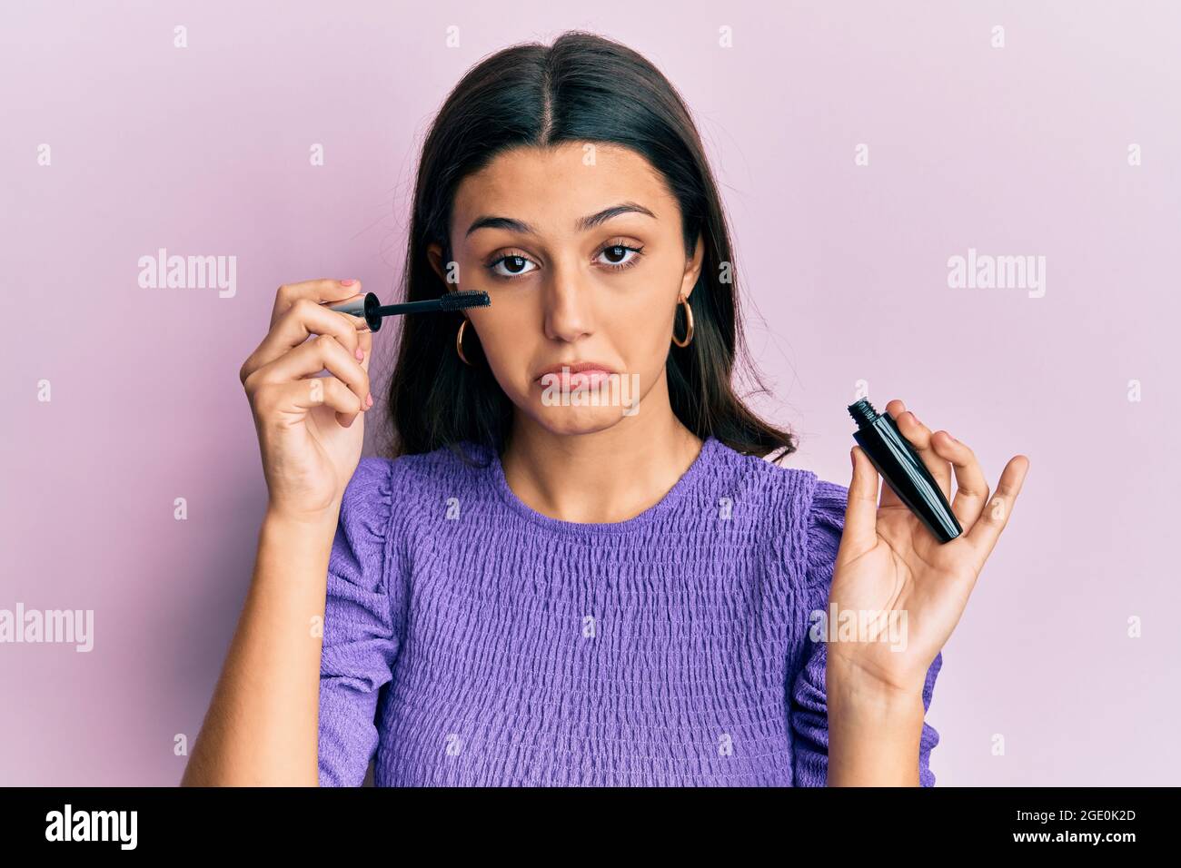 Young hispanic woman holding eyelashes curler depressed and worry for ...