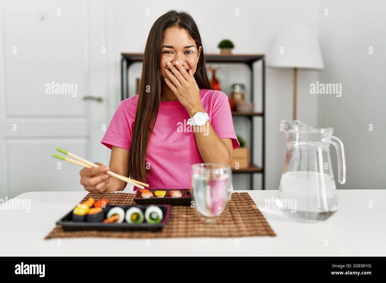 Young brunette woman eating sushi using chopsticks laughing and ...