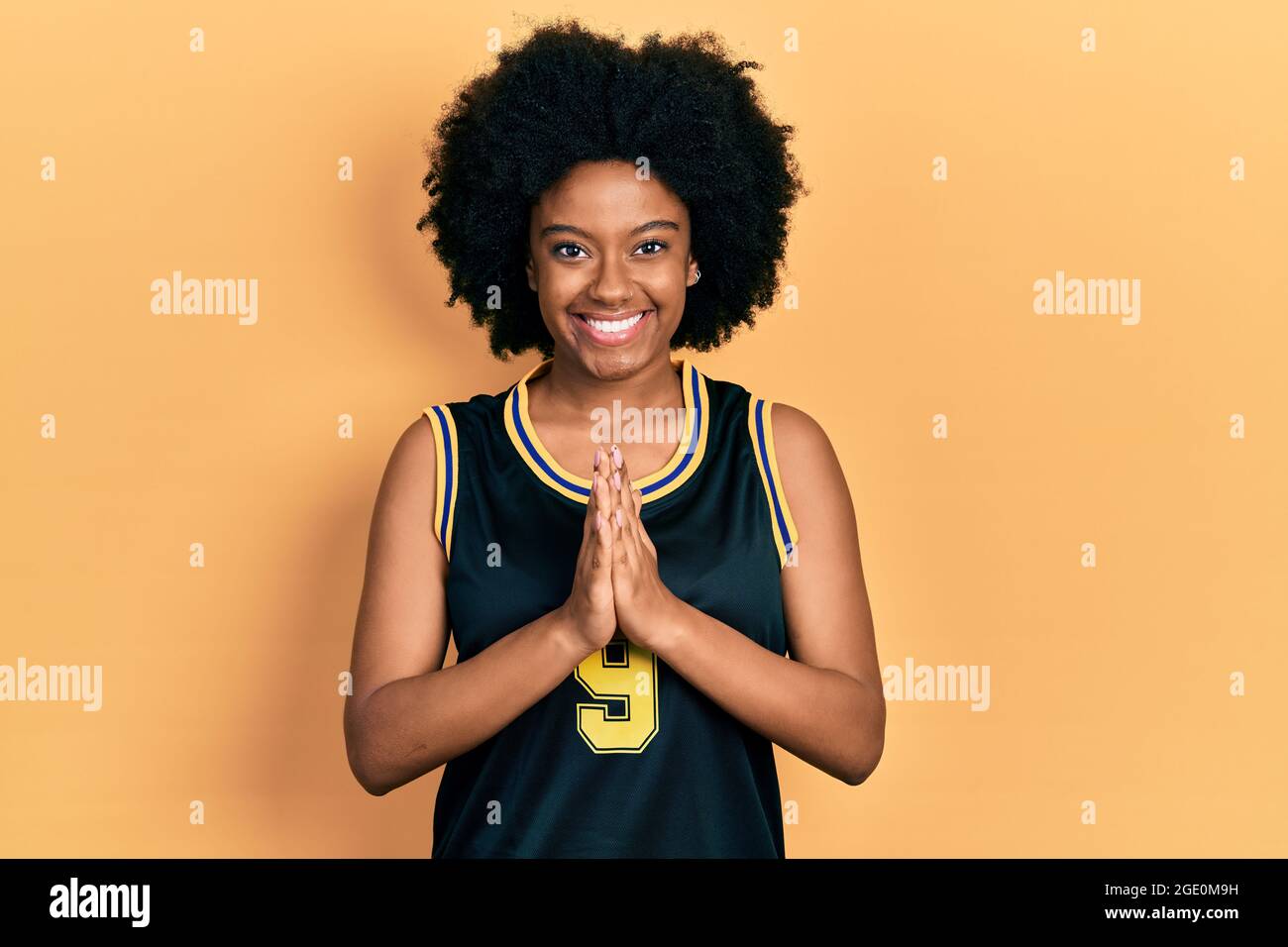 Young african american woman wearing basketball uniform praying with ...