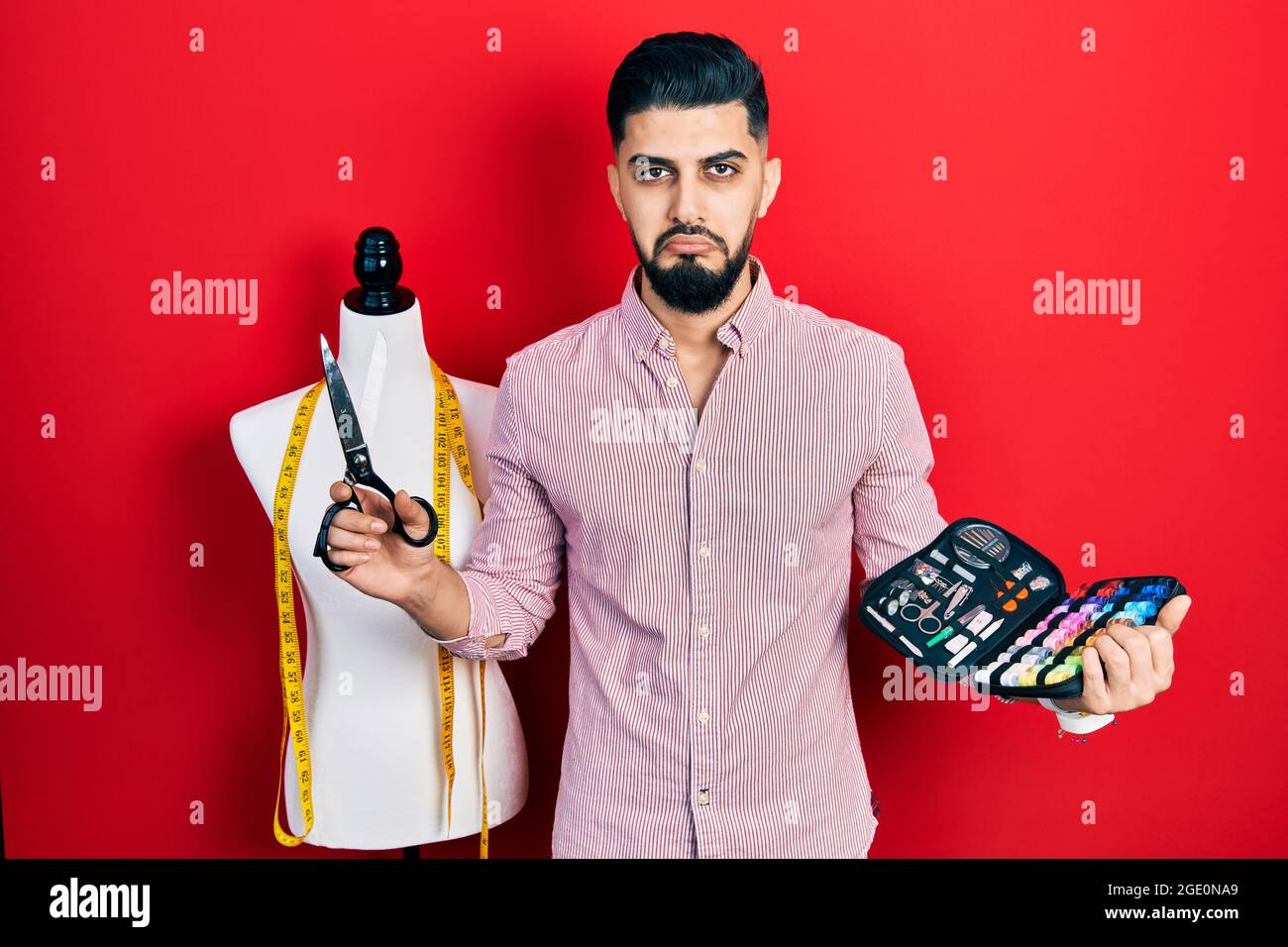Handsome tailor man with beard holding sew kit and scissors depressed ...