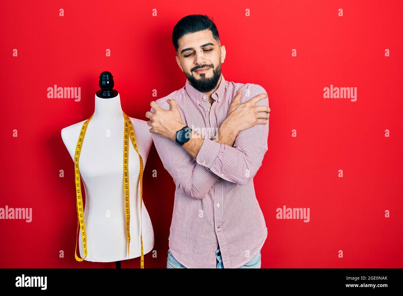 Handsome tailor man with beard standing by manikin hugging oneself ...