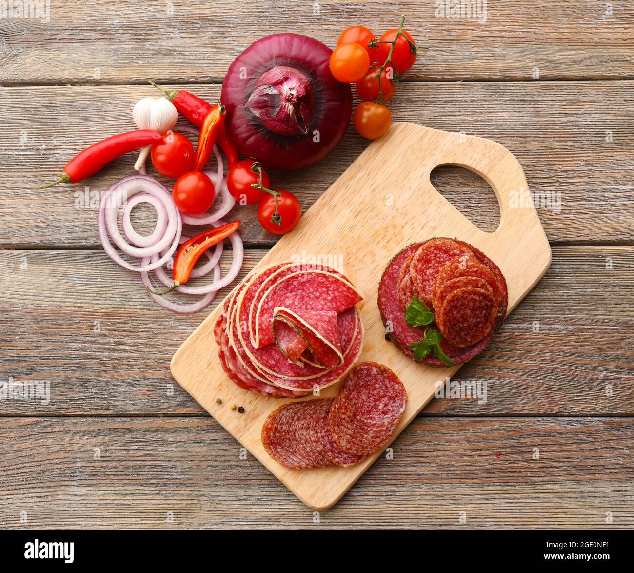 Sliced salami with chili pepper, cherry tomatoes, onion and spices on ...