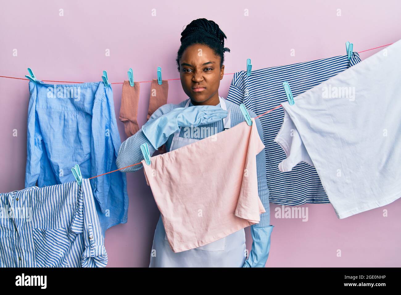 African american woman with braided hair washing clothes at clothesline ...