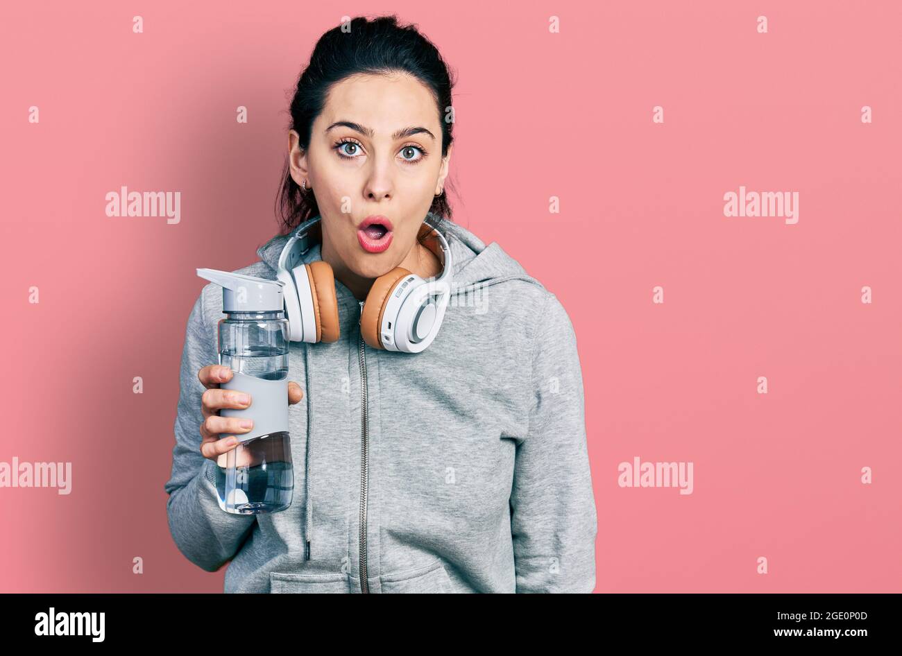 Young hispanic woman wearing sportswear holding water bottle using ...