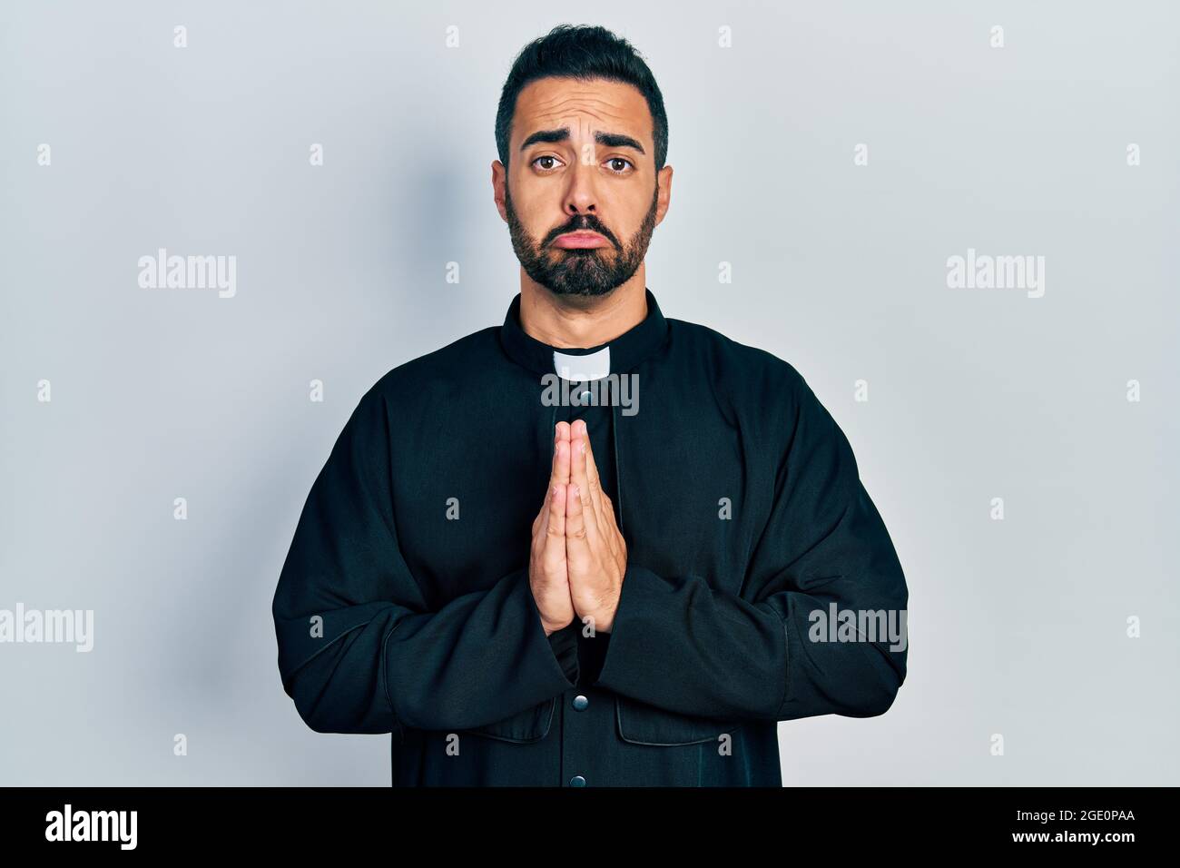 Handsome hispanic priest man with beard standing over isolated ...