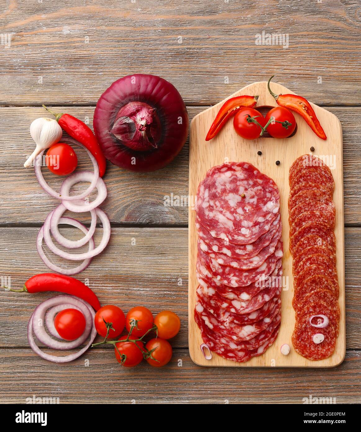 Sliced salami with chili pepper, cherry tomatoes, onion and spices on ...