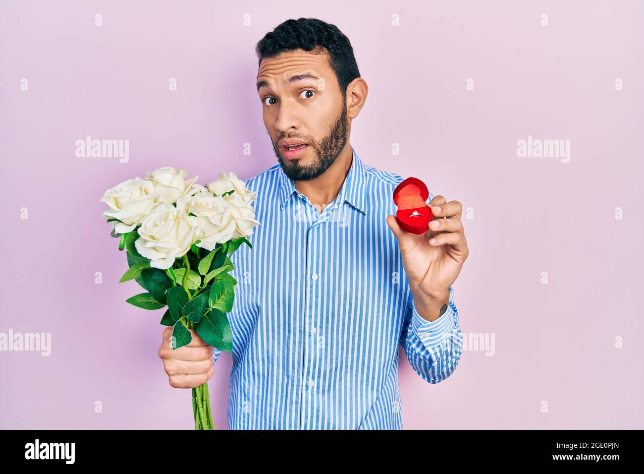 Hispanic man with beard holding bouquet of flowers and engagement ring ...