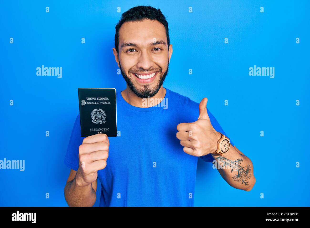Hispanic man with beard holding italy passport doing happy thumbs up ...