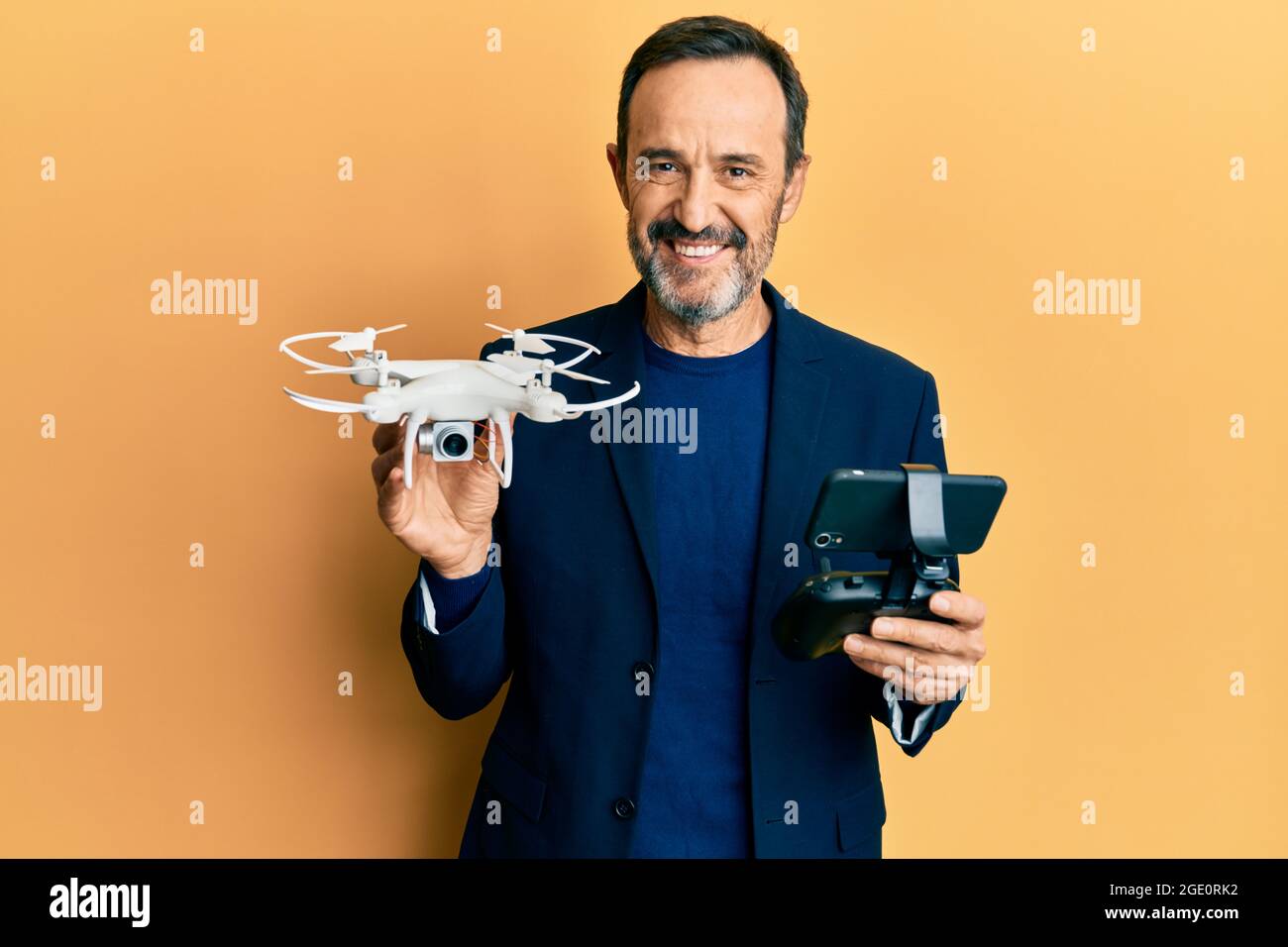 Middle age hispanic man using drone smiling with a happy and cool smile ...