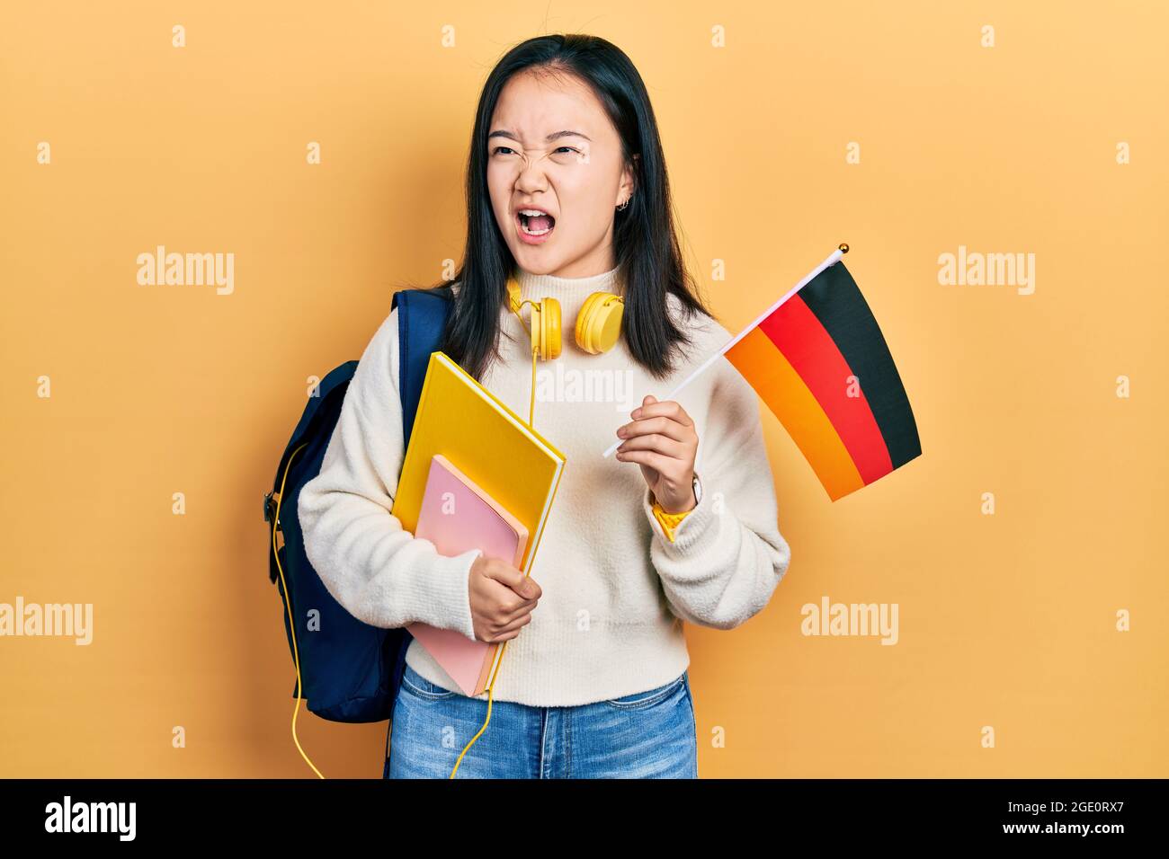 Young chinese girl exchange student holding germany flag angry and mad ...