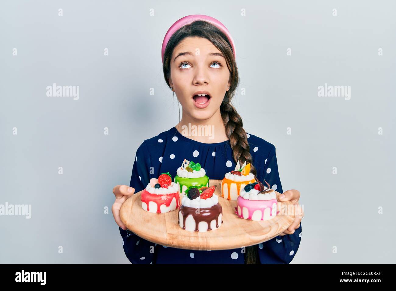 Young brunette girl holding sweet pastries angry and mad screaming ...