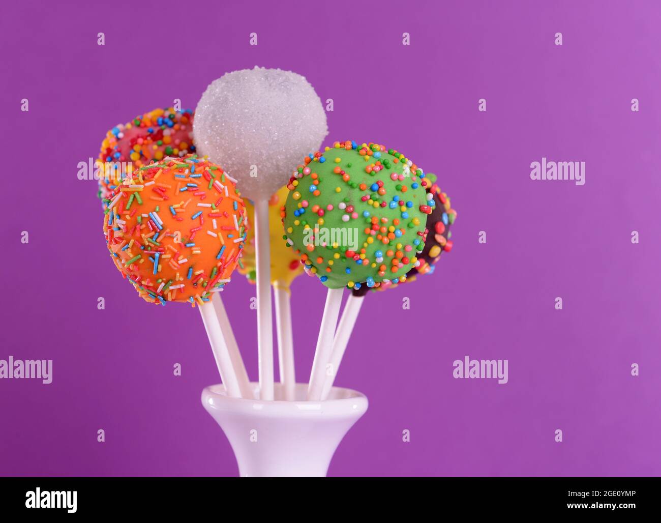 Sweet cake pops in vase on purple background Stock Photo - Alamy