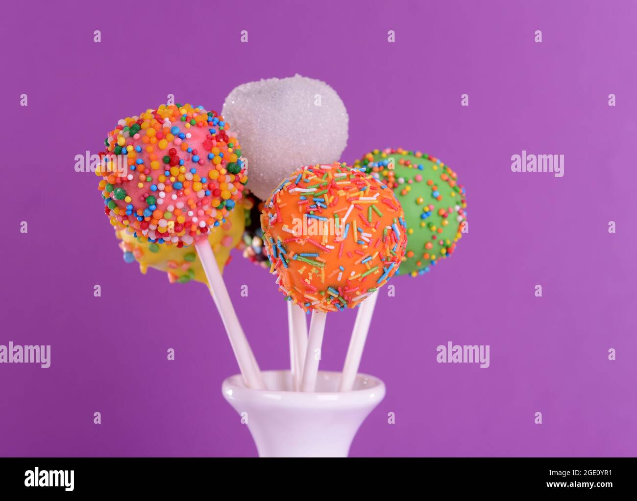Sweet cake pops in vase on purple background Stock Photo - Alamy