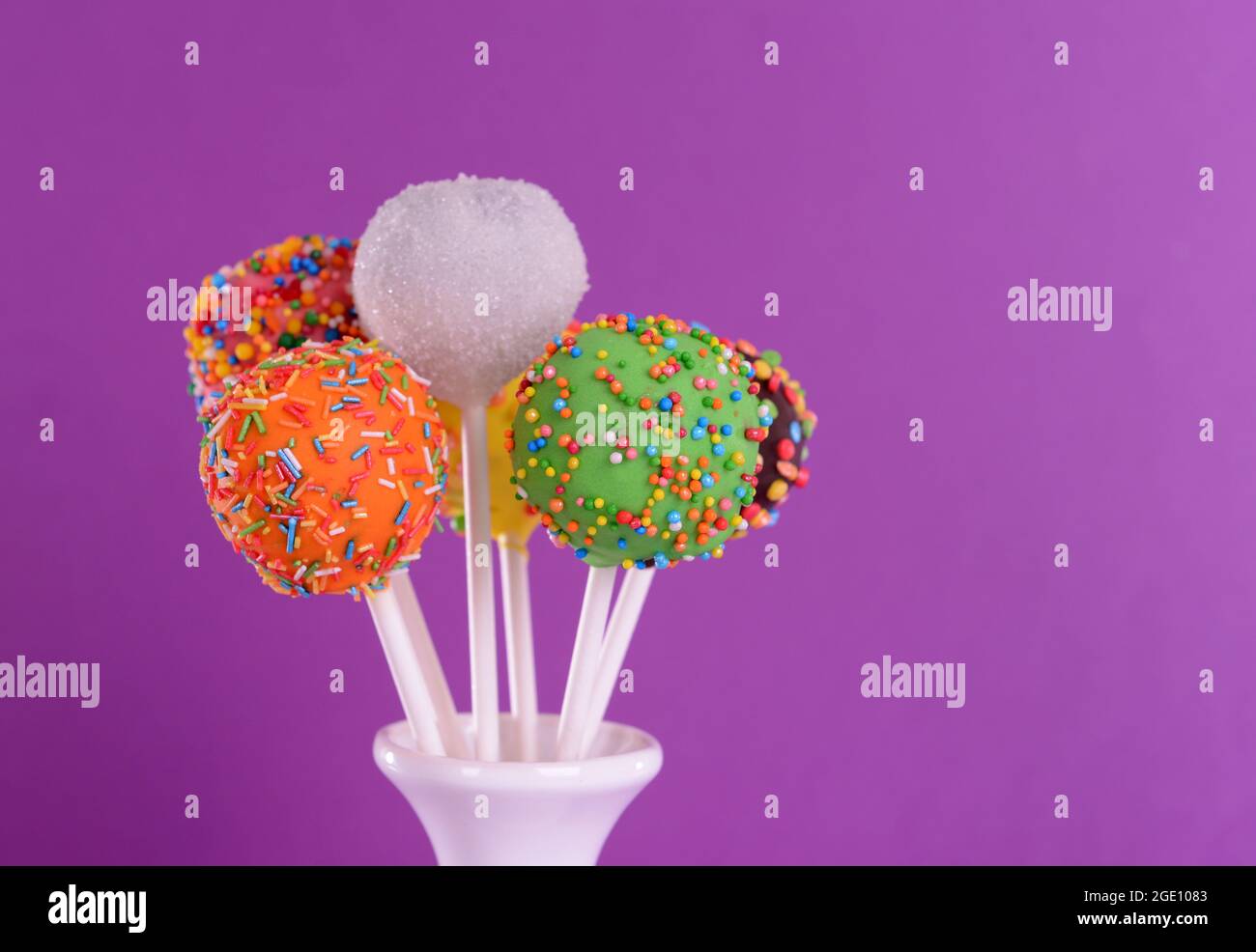 Sweet cake pops in vase on purple background Stock Photo - Alamy