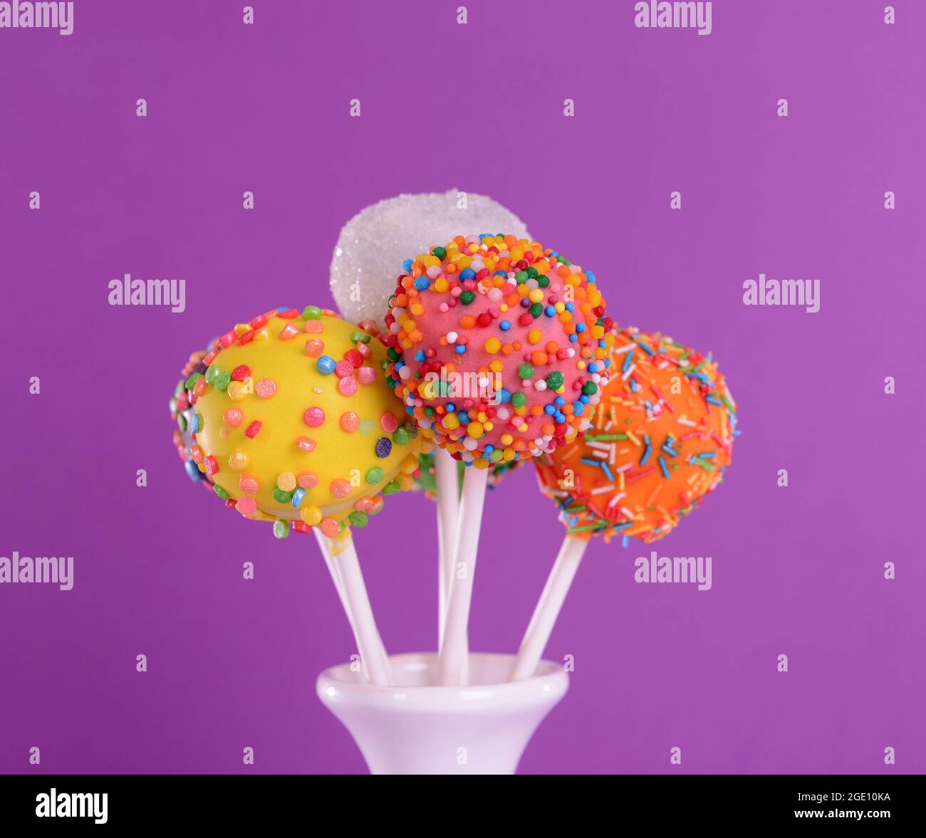 Sweet cake pops in vase on purple background Stock Photo - Alamy