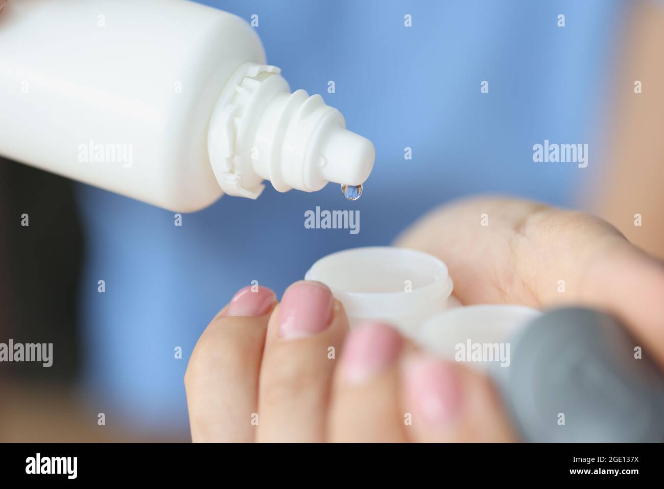 Woman pouring lens solution from bottle into plastic container closeup ...