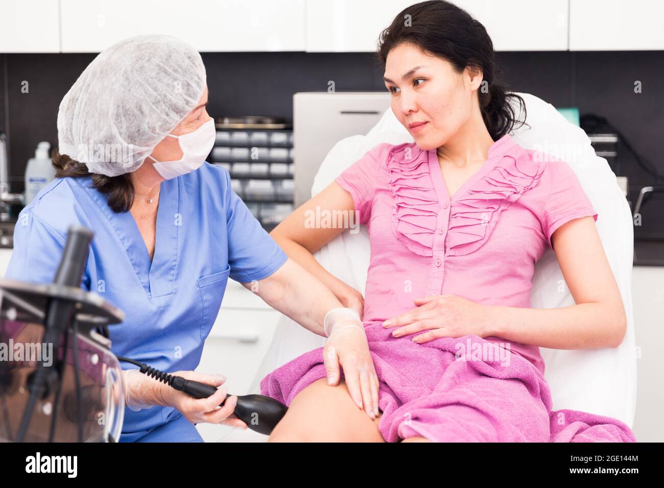 Asian woman receiving professional hardware treatment of thighs skin ...