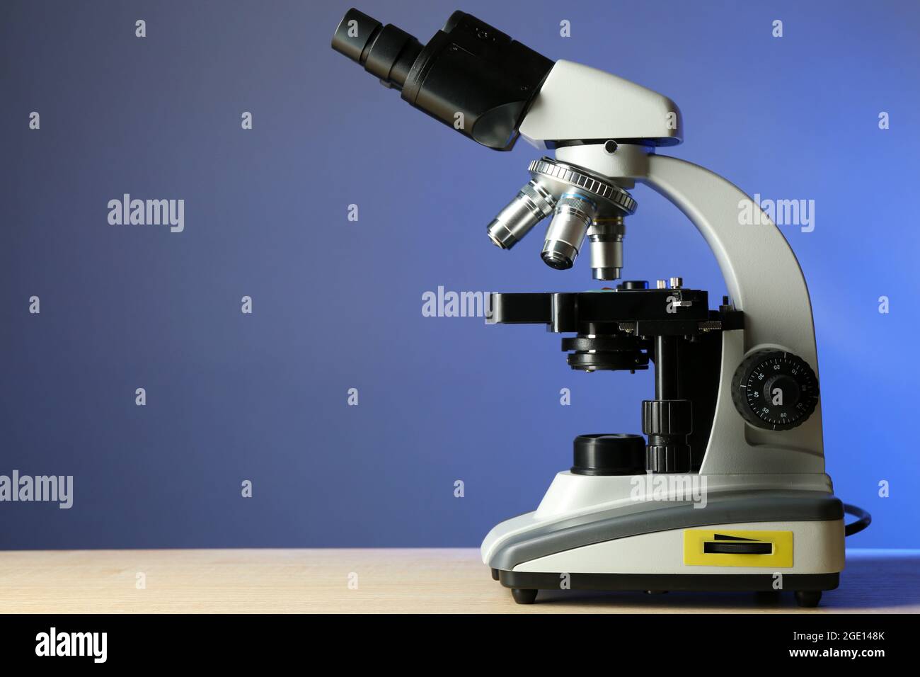 Microscope on table, on color background Stock Photo - Alamy