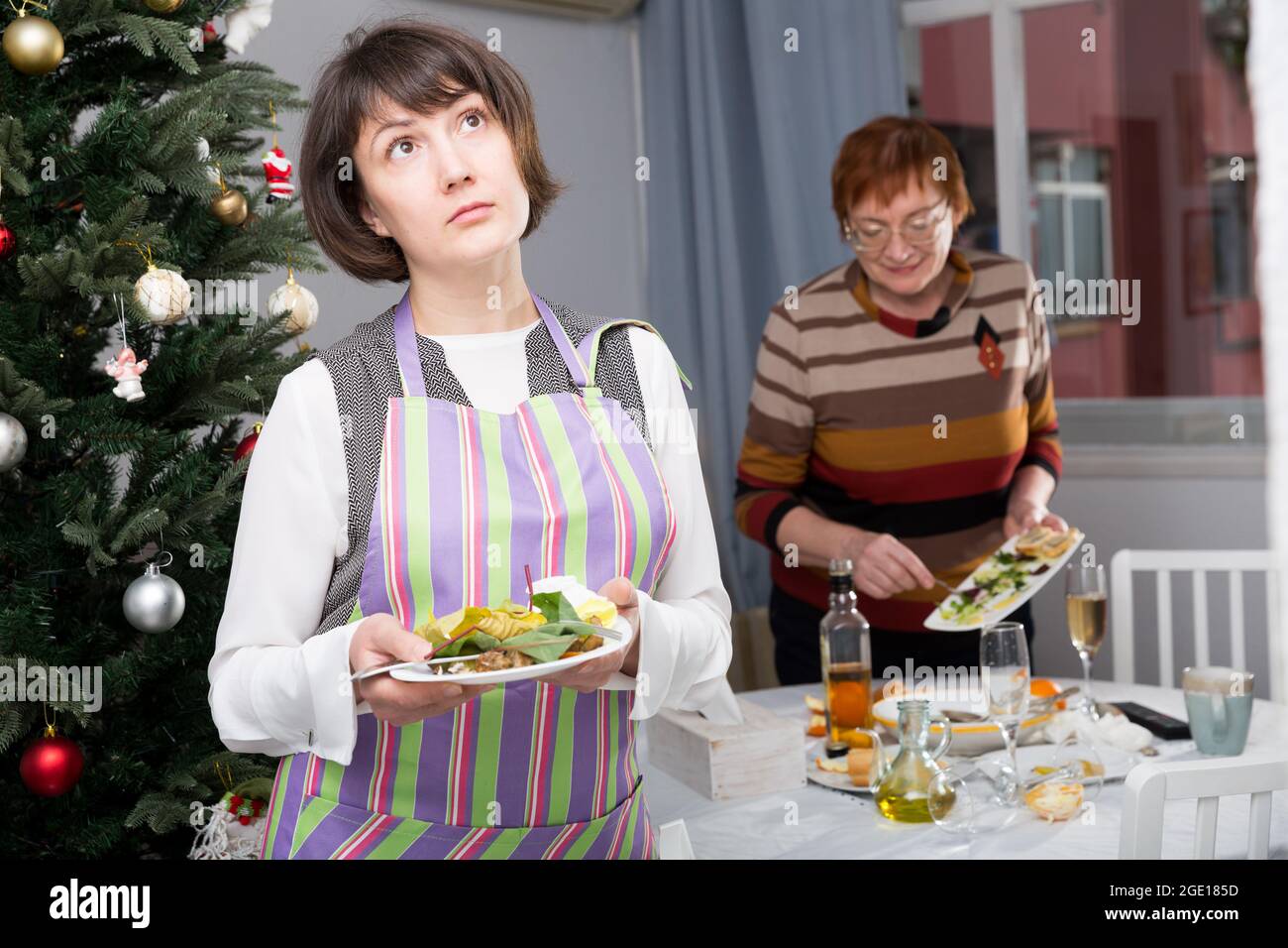 Dreamy woman clearing table with mother Stock Photo - Alamy