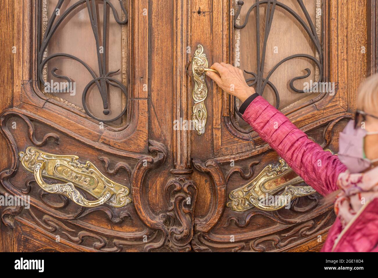Adult woman with face mask and sunglasses holding the door handle of ...
