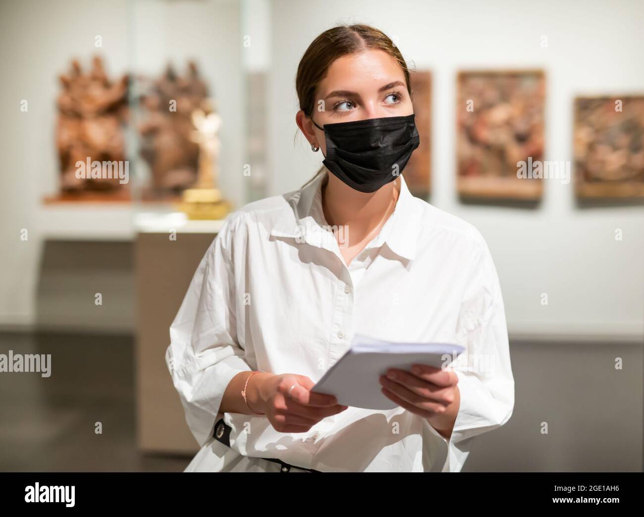 Woman wearing face mask observing artworks in museum Stock Photo - Alamy