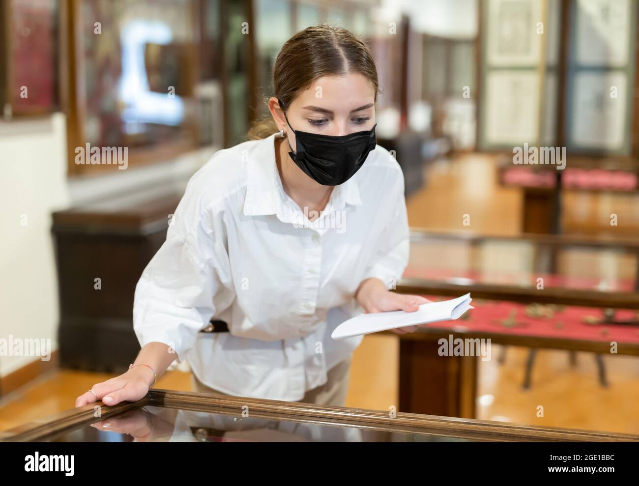 Woman exploring artworks in glass case in museum Stock Photo - Alamy