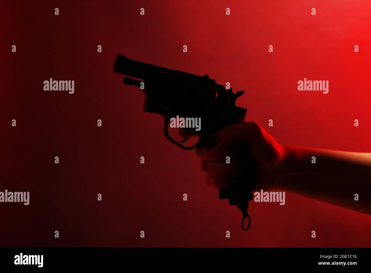 Hand holding gun on red background Stock Photo - Alamy