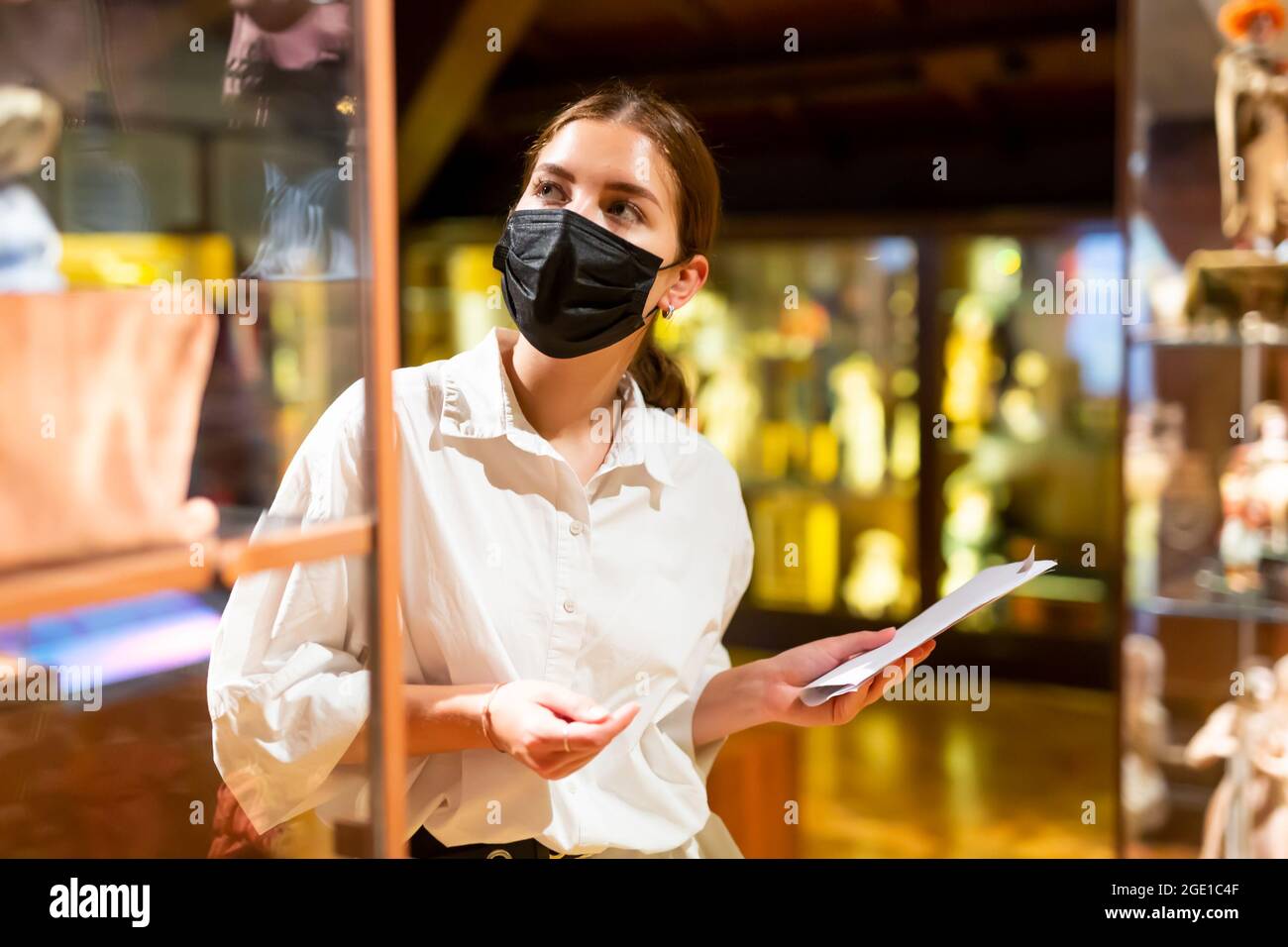Woman exploring artworks in glass case in museum Stock Photo - Alamy