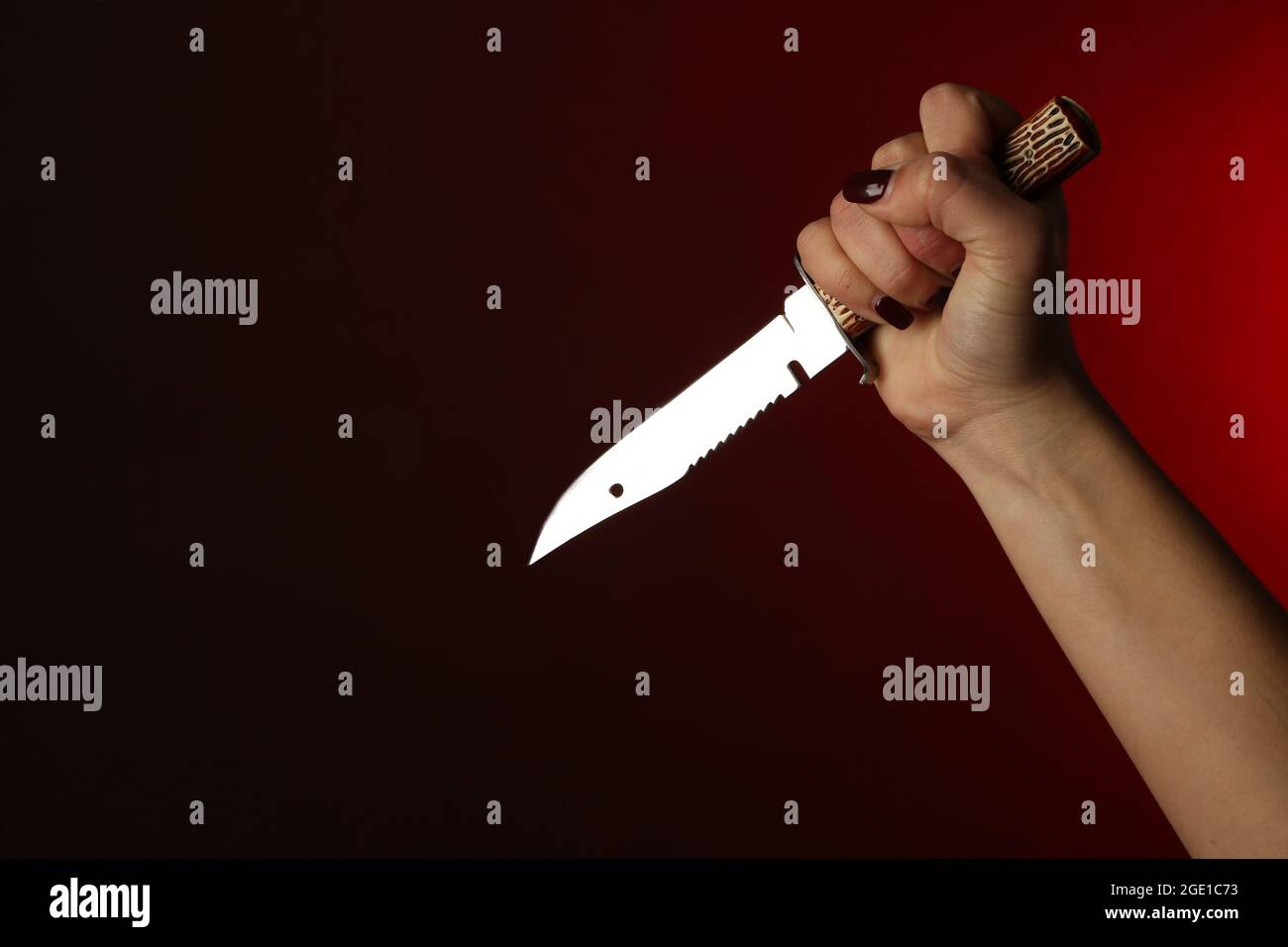 Female hand holding knife on red background Stock Photo - Alamy