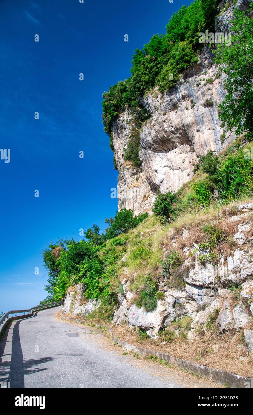 Pathway below the rocky cliff on blue sky background Stock Photo - Alamy
