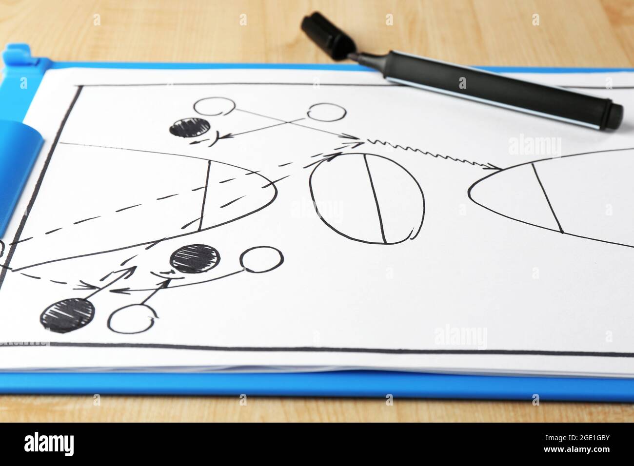 Scheme basketball game on clip board paper with marker and wooden table ...