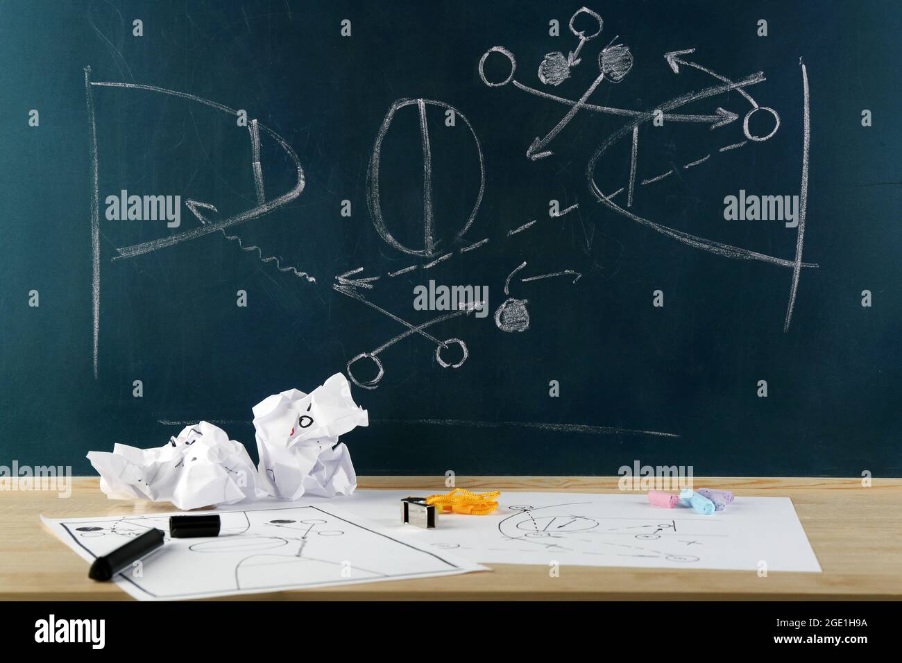 Table with sheets of paper and blackboard with scheme basketball game ...