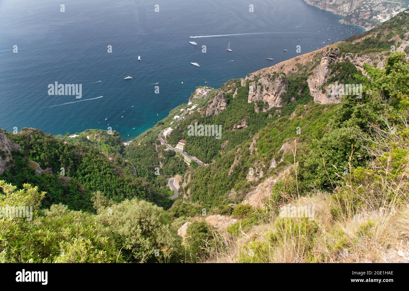 Aerial shot of a beautiful coastal cliff with sailing yachts on water ...