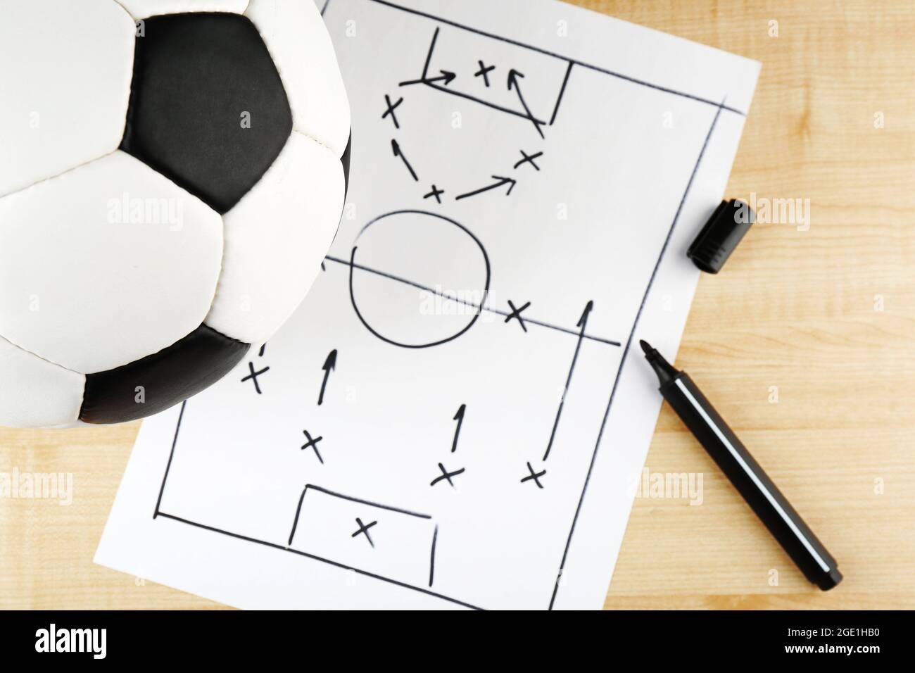 Scheme football game on sheet of paper and wooden table background ...