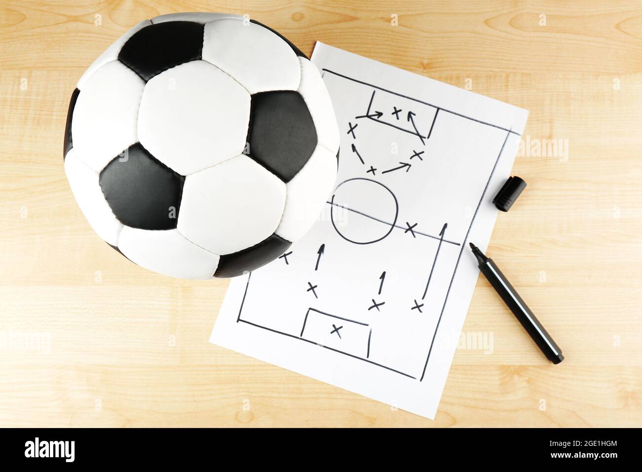 Scheme football game on sheet of paper and wooden table background ...