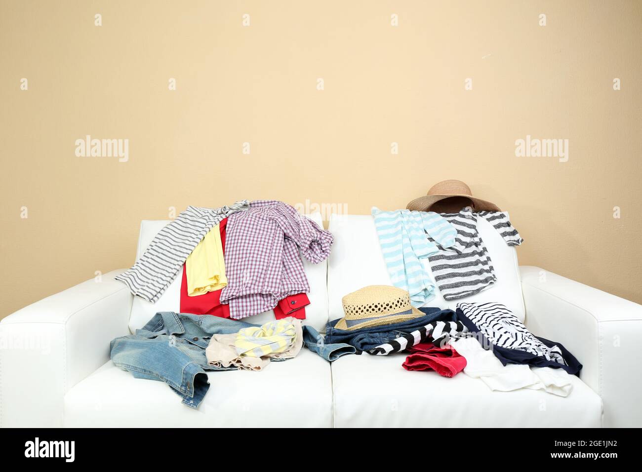Messy clothing on white sofa, on light wall background Stock Photo - Alamy