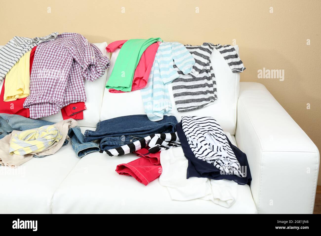 Messy clothing on white sofa, on light wall background Stock Photo - Alamy