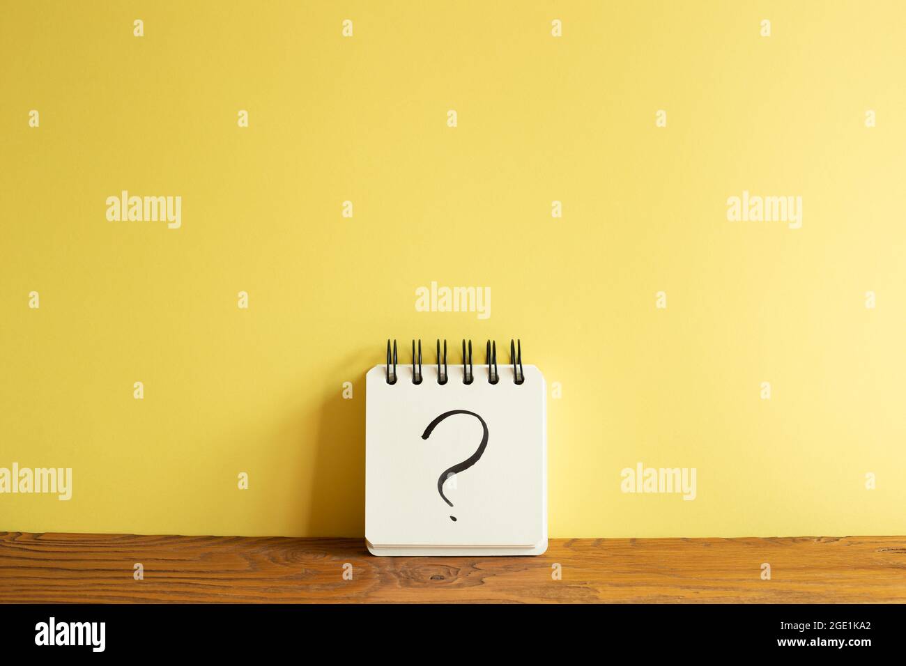 Notebook with question mark on wooden desk. yellow wall background ...