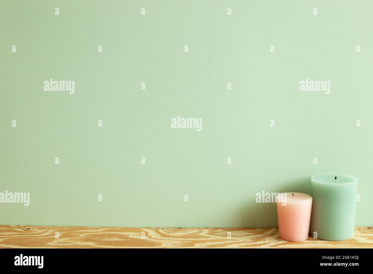 Color candles on wooden table. green wall background. home interior ...