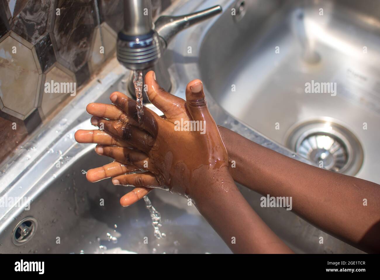 Student or pupil practicing hygienic hand washing with soap under ...