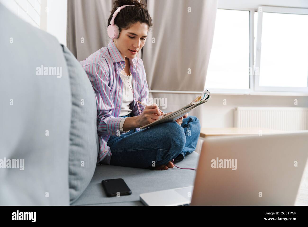 Portrait of a mid aged young woman in headphones studying while sitting ...