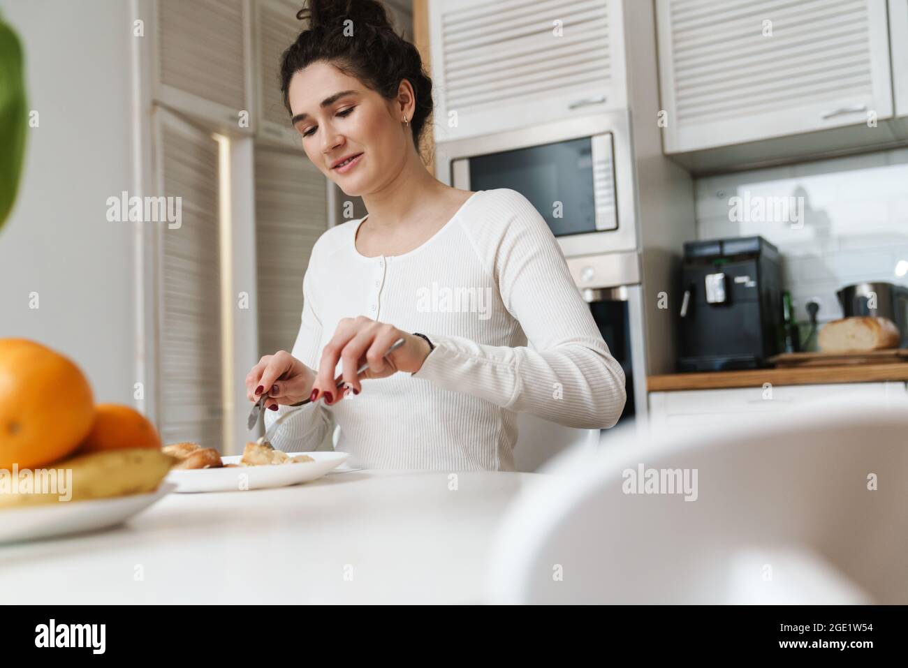 The smiling woman cutting food on plate while sitting at table in the ...
