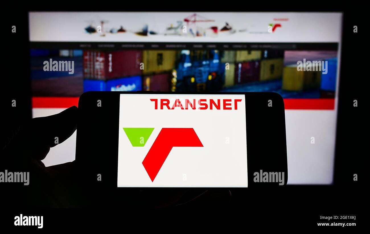 Person holding mobile phone with logo of South African logistics company Transnet SOC Ltd. on ...