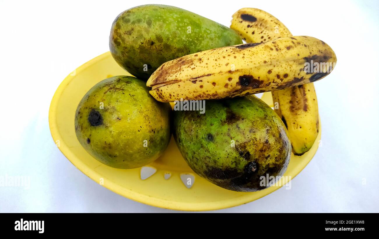 Three ripe mangoes and bananas in a basket isolated on white background ...